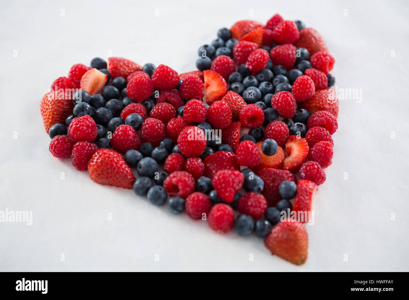 Close-up of various fruits forming a heart shape against white ...
