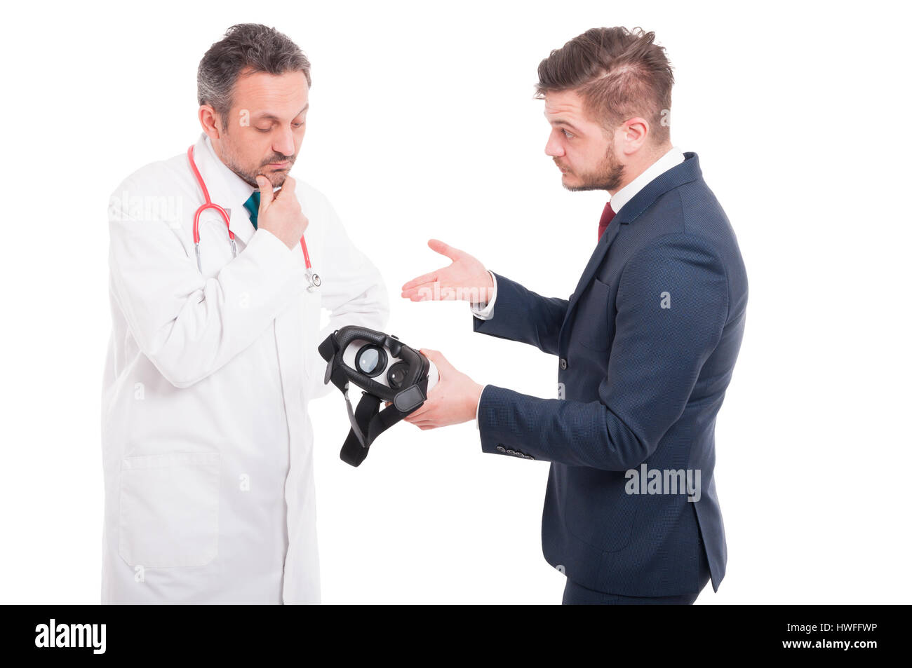 Male doctor with businessman holding futuristic device on white studio ...