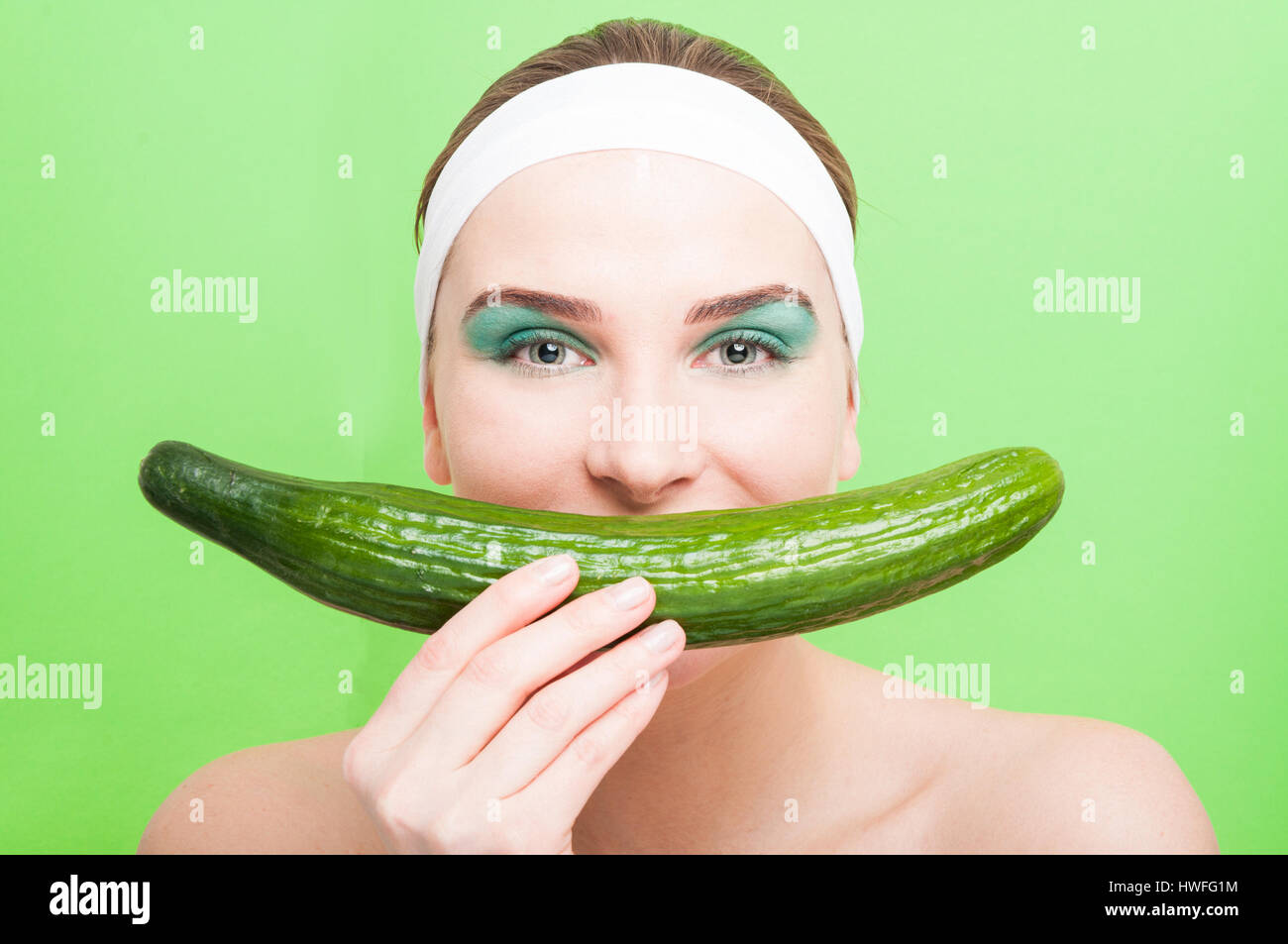 Pretty Woman With Extravagant Makeup Holding Fresh Cucumber Before Her