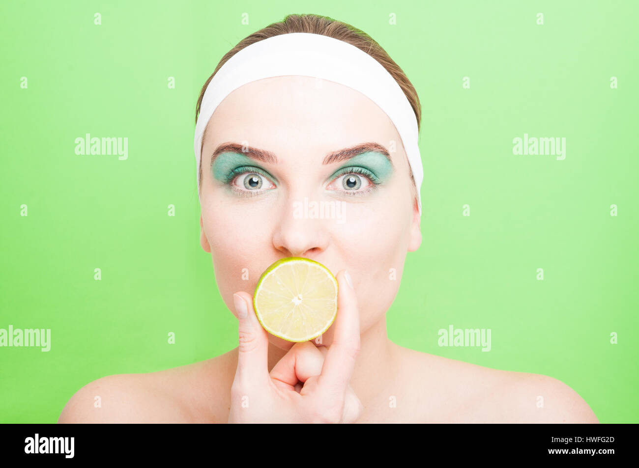 Pretty girl with makeup holding slice of lemon before her mouth as ...