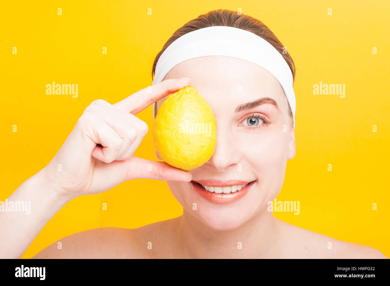 Pretty female covering her eye with a fresh lemon as purity and ...