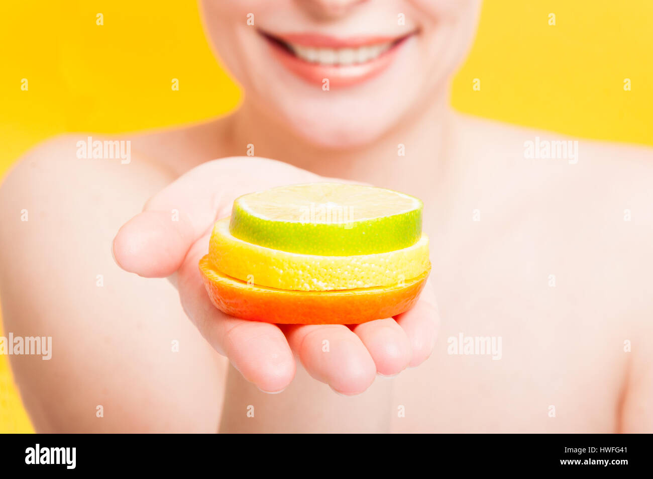Closeup hand of female with citrus on yellow background holding slices ...