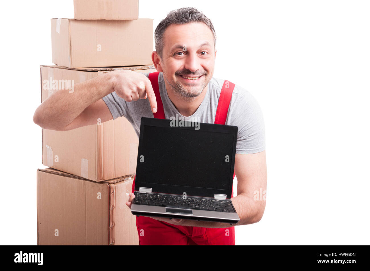 Mover guy holding and pointing blank screen laptop with cardboard boxes ...