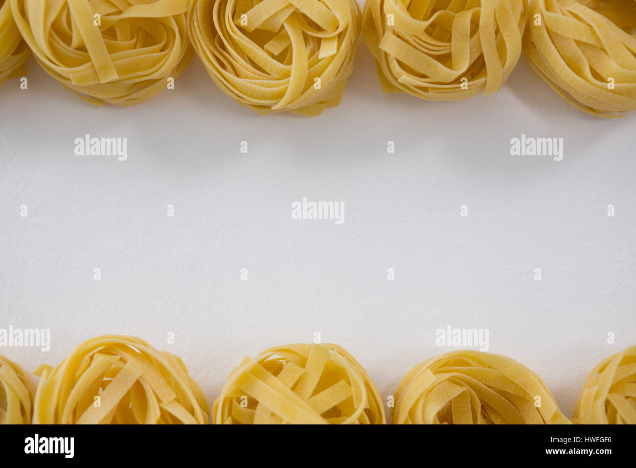 Fettuccine pasta arranged in a row on white background Stock Photo - Alamy