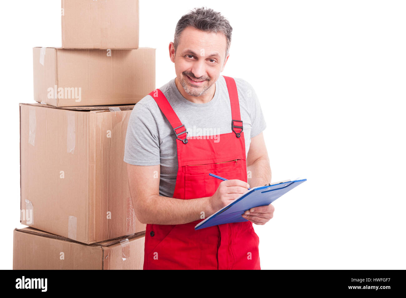 Mover guy smiling counting or writing on clipboard with cardboard boxes ...