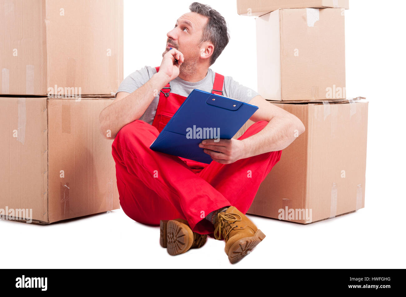 Mover guy sitting on the floor holding clipboard surrounded by boxes ...