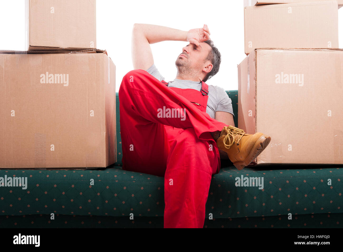 Tired mover man sitting on couch with cardboard boxes around and hand ...