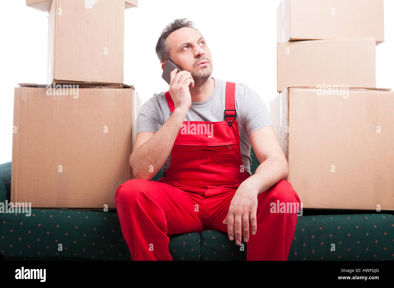 Mover man sitting on couch talking at phone being serious isolated on ...