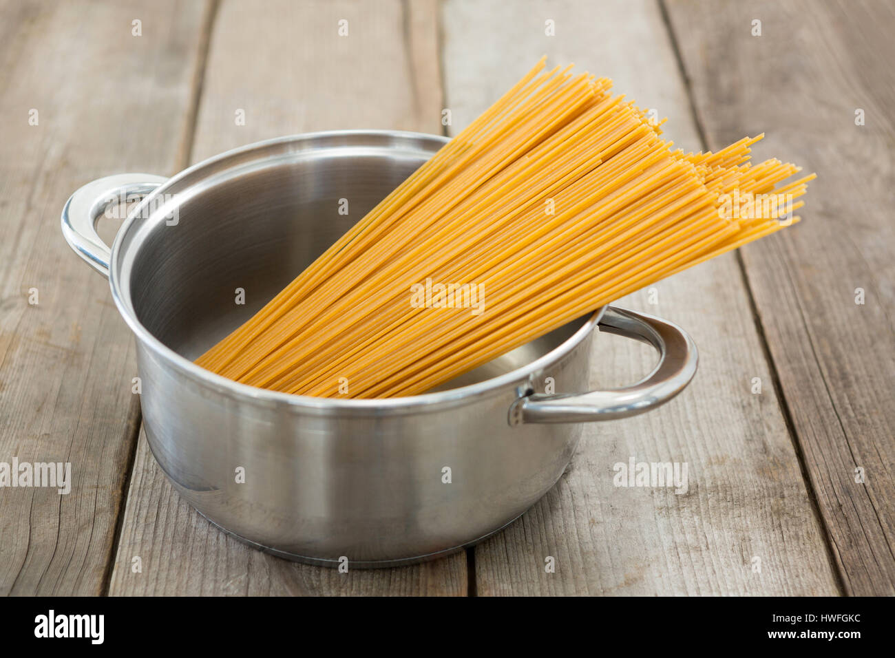 Spaghetti pasta in utensil on wooden surface Stock Photo - Alamy