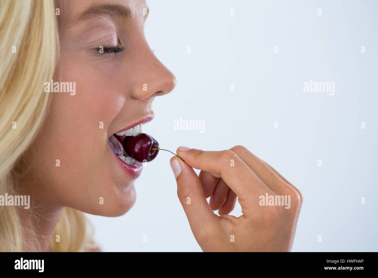 Clos-up of beautiful woman eating cherry against white background Stock ...