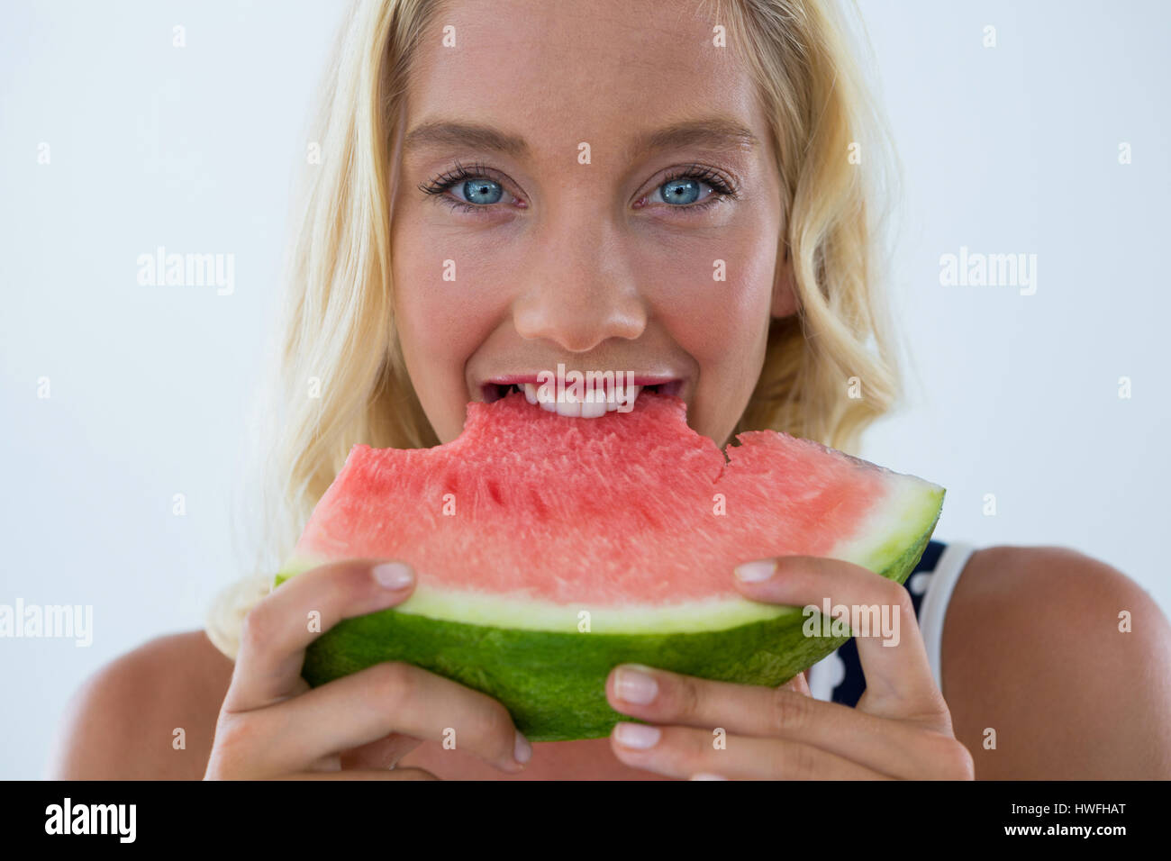 Portrait of beautiful woman eating watermelon against white background ...