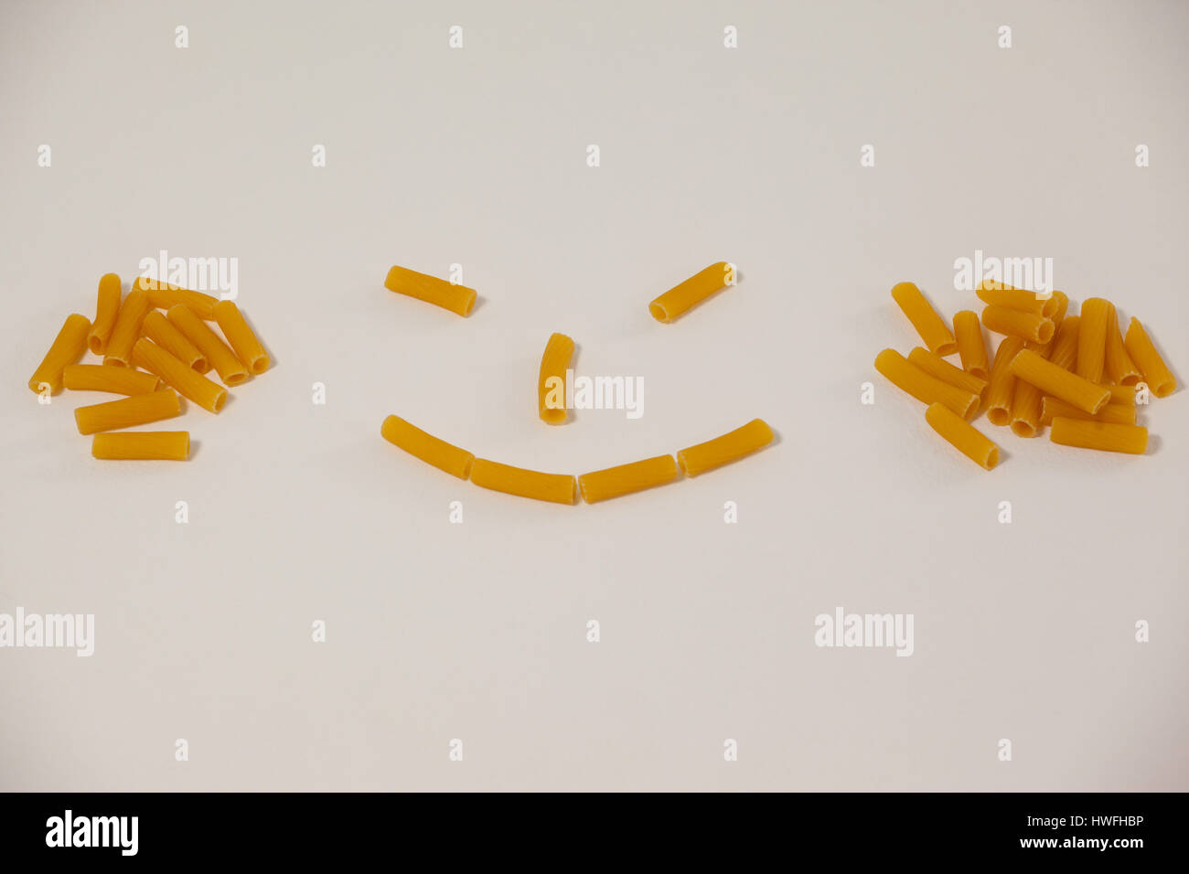 Smiley face made out of pennette pasta on white background Stock Photo ...