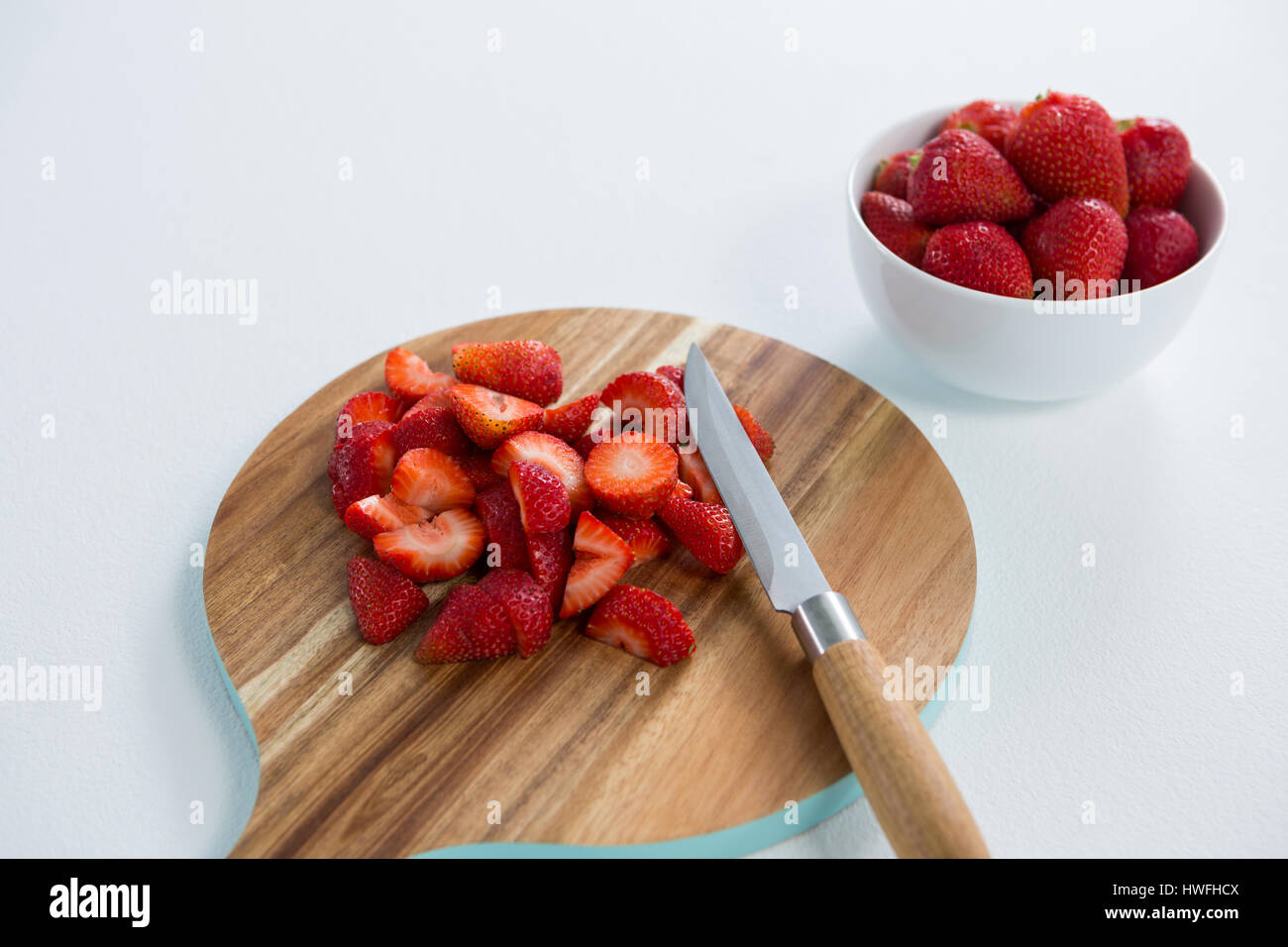 Slices of strawberries on chopping board against white background Stock ...