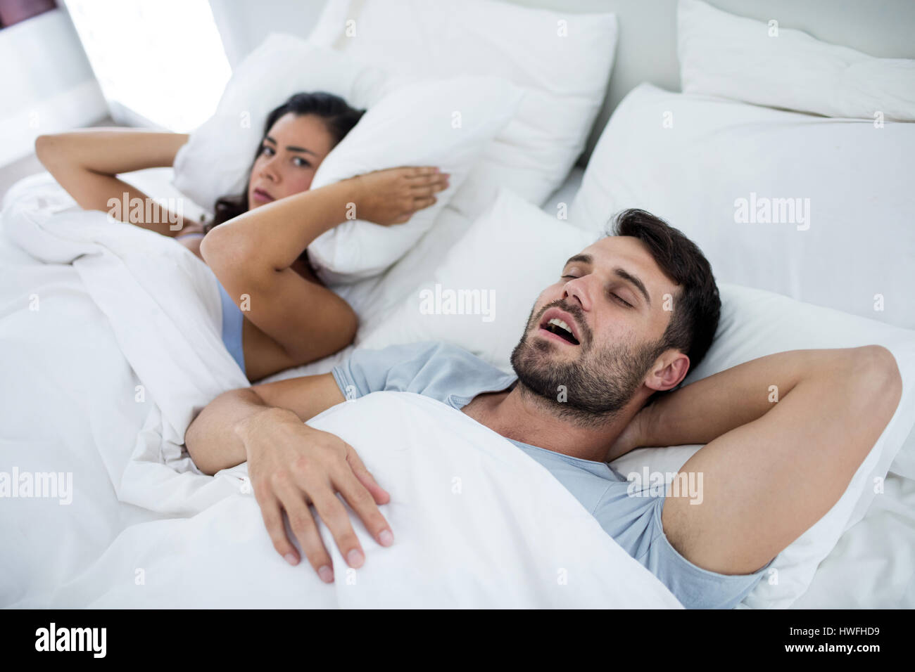 Woman getting disturbed with man snoring on bed in bedroom Stock Photo ...