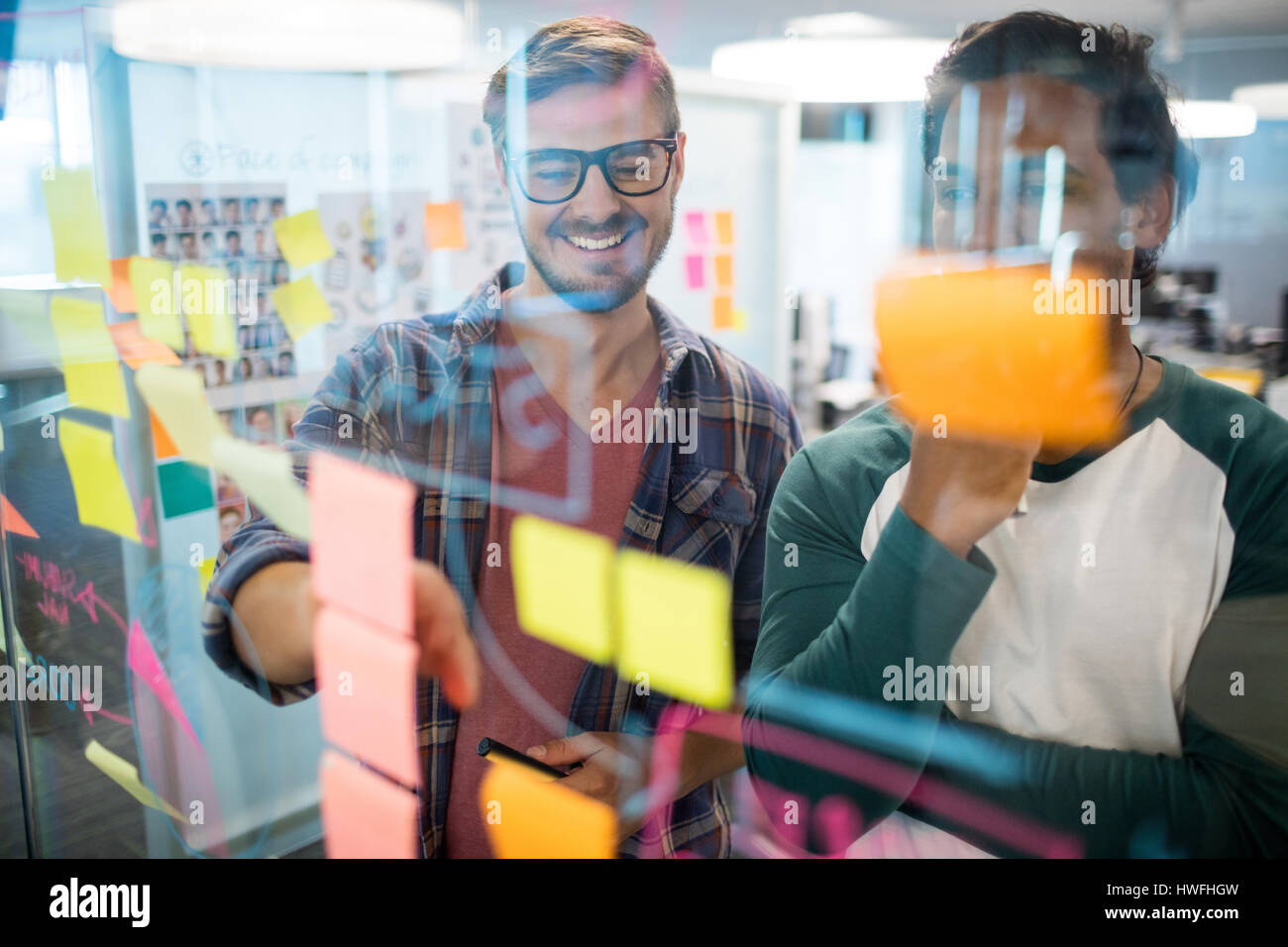 Smiling creative business team reading sticky notes in office Stock ...