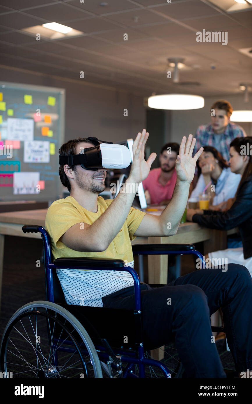 Physically disabled man on wheelchair using VR headset in office Stock ...