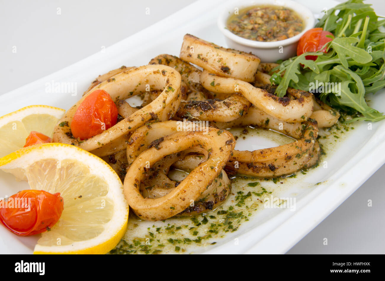 Seasoned calamari with lemon, tomatoes and spices Stock Photo - Alamy