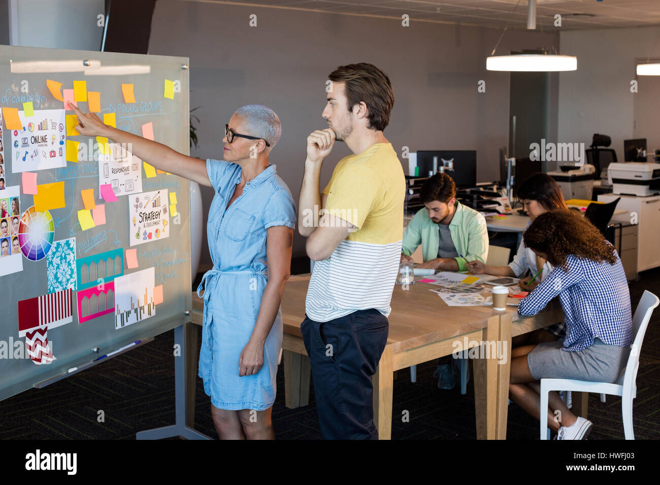 Creative business people looking at sticky notes on glass board Stock ...
