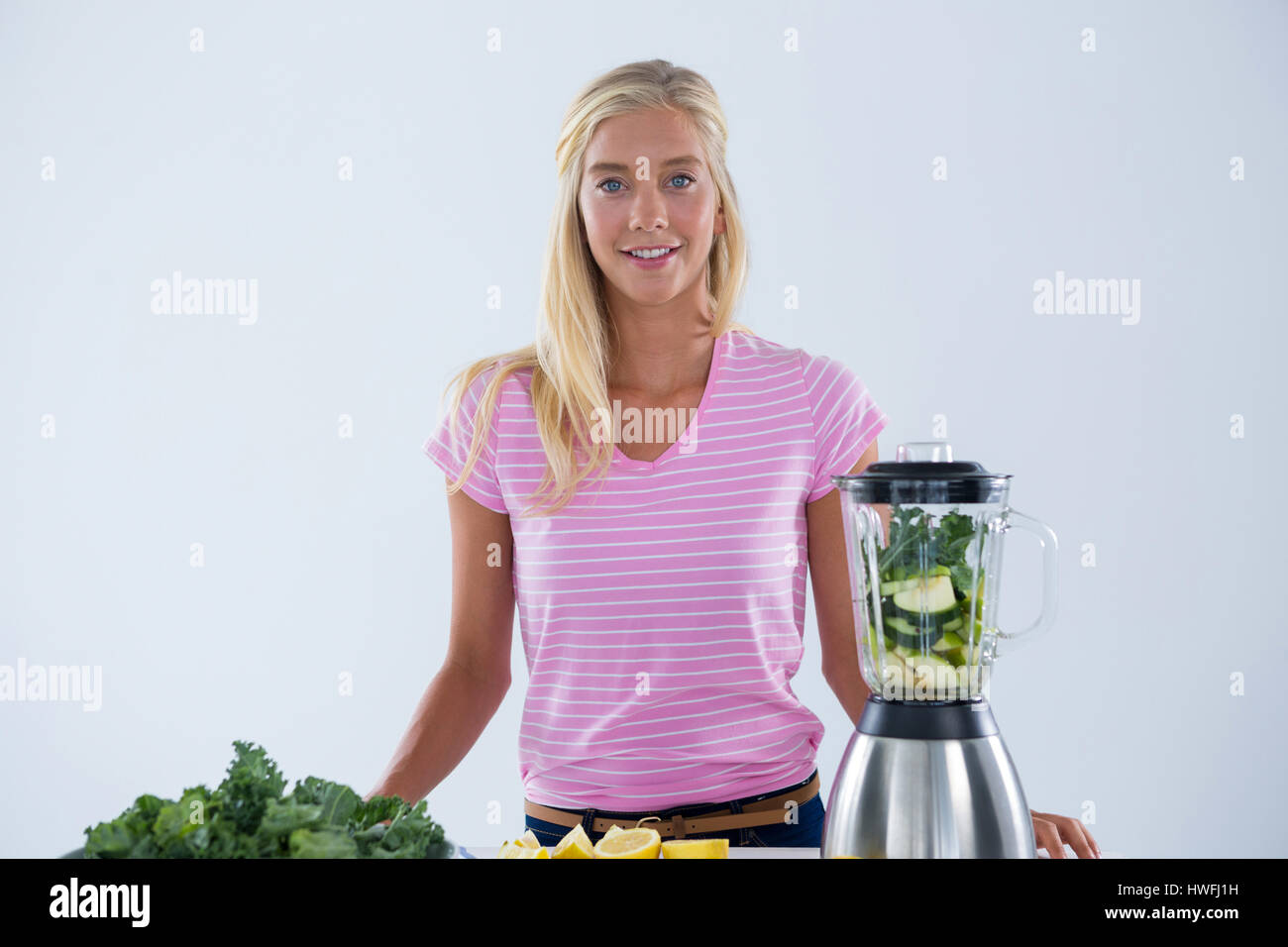 Portrait of smiling woman standing near kitchen worktop against white background Stock Photo - Alamy