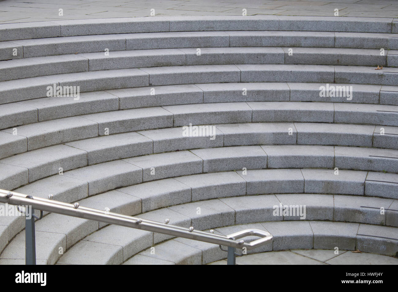 Curved amphitheatre-style steps with straight metal handrail Stock ...
