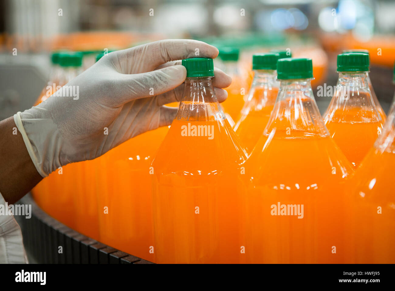 Male worker examining bottles in juice factory Stock Photo - Alamy