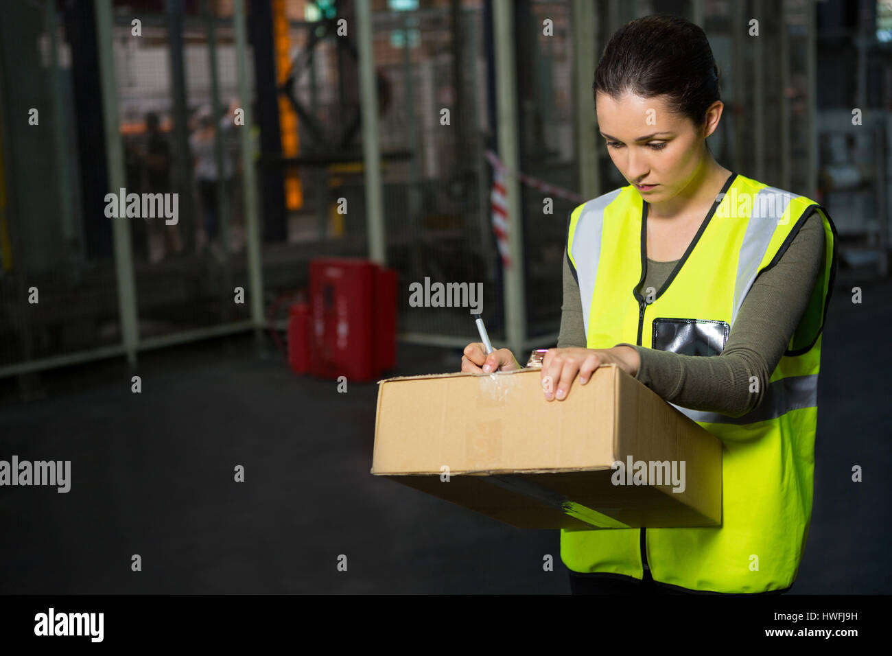 Confident female worker writing on box in warehouse Stock Photo - Alamy