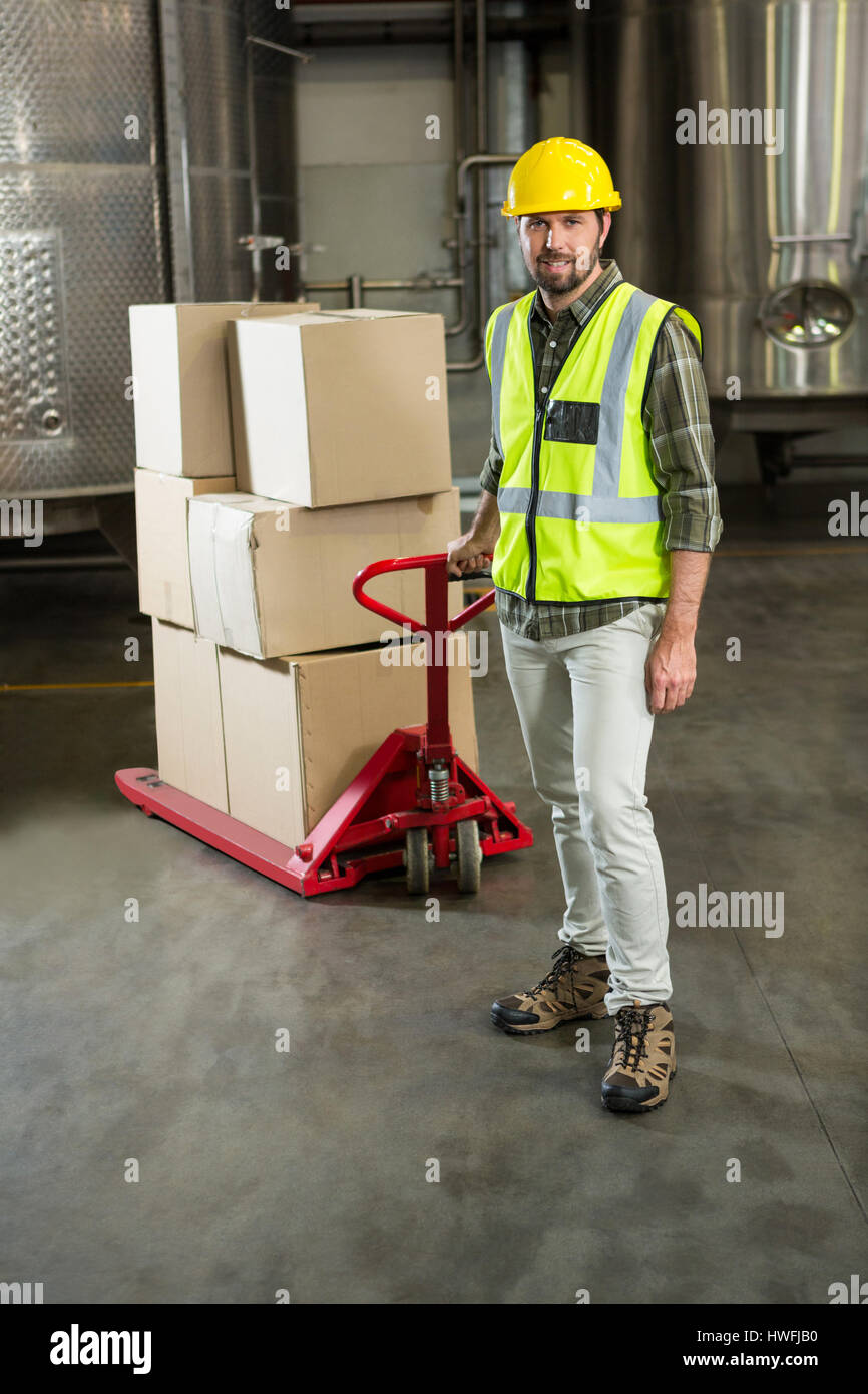 Full length portrait of male worker pulling trolley in warehouse Stock ...