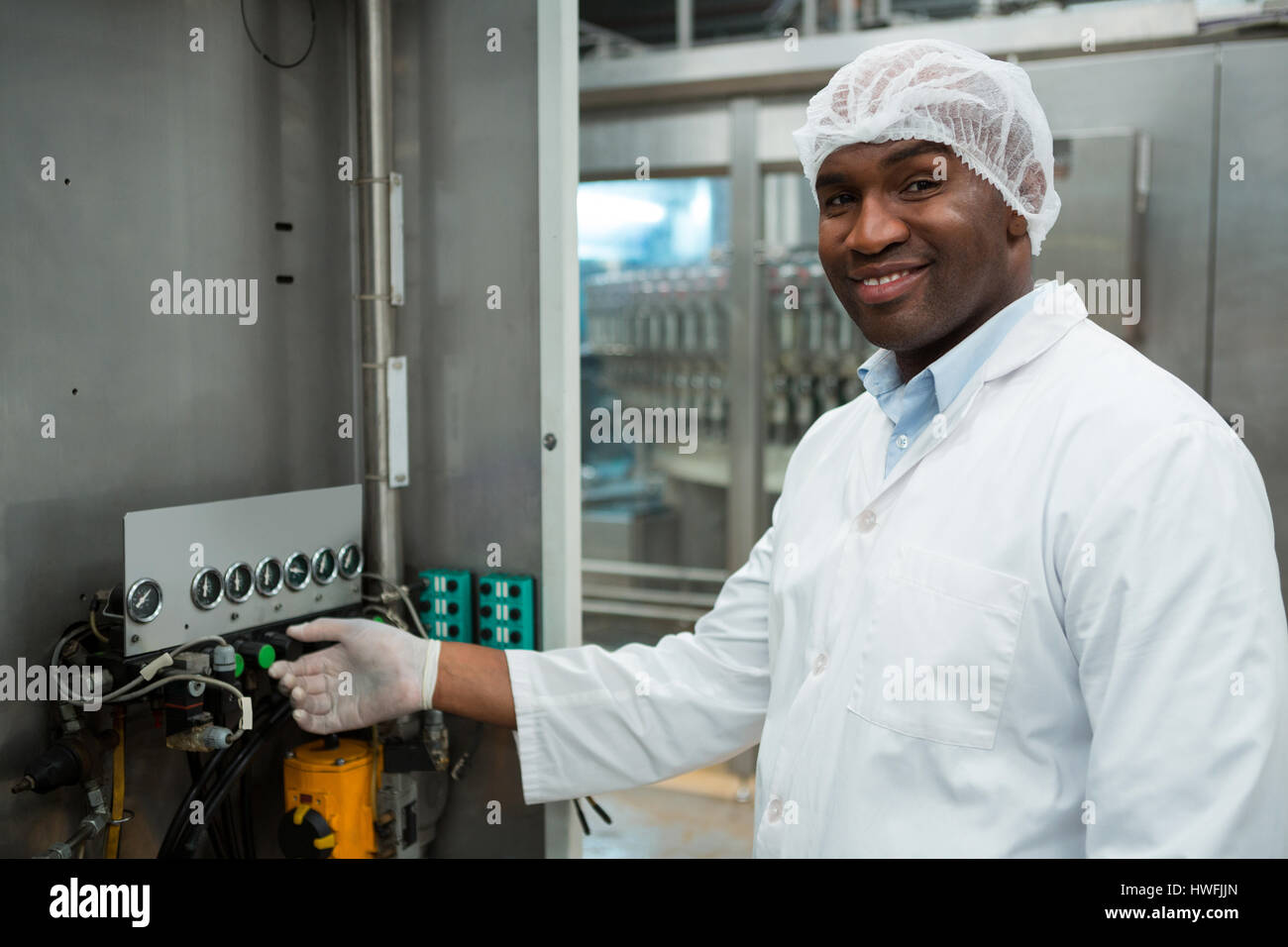 Portrait of confident male worker operating machine in juice factory ...