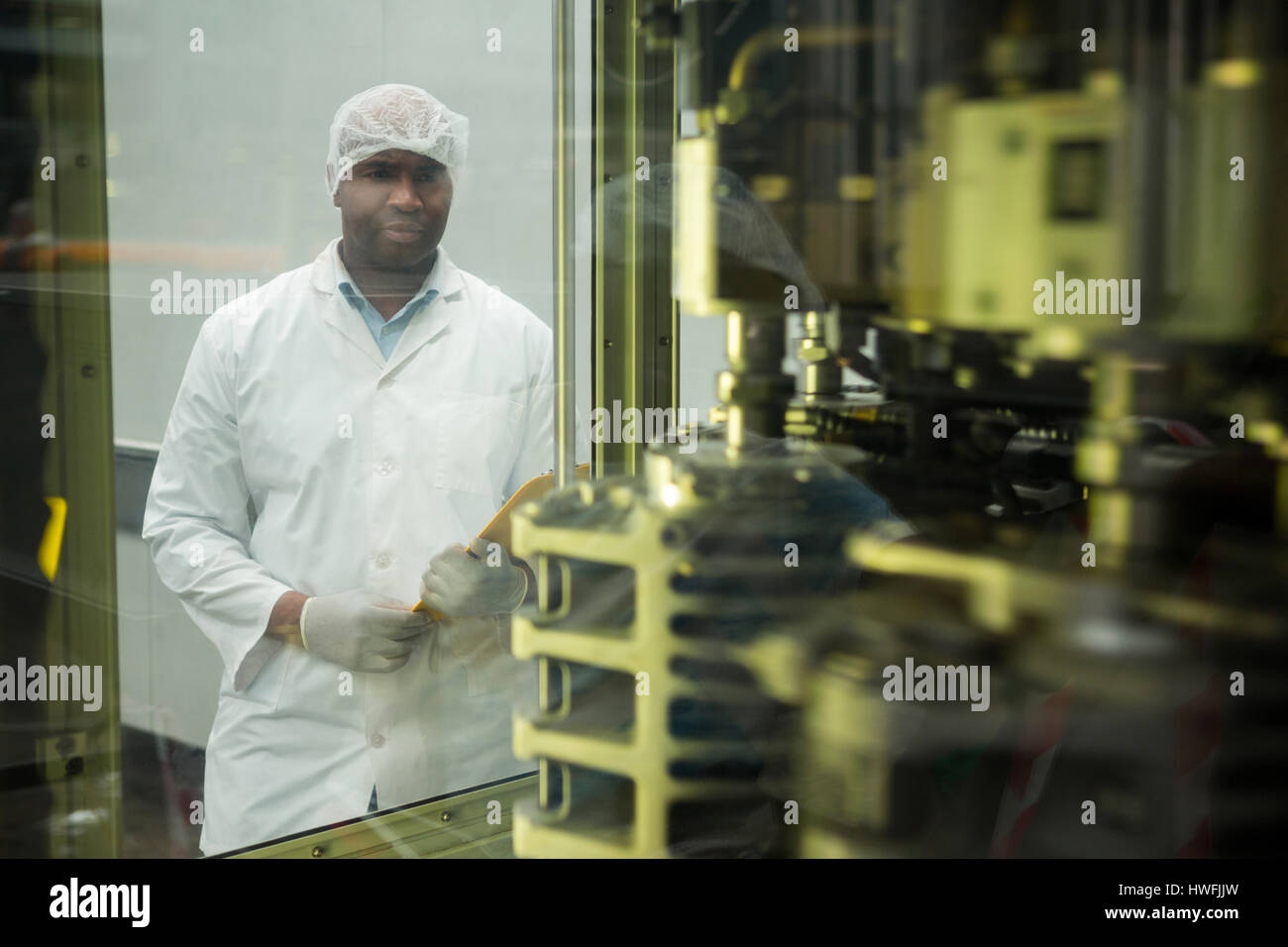 Male worker seen through machinery in juice factory Stock Photo - Alamy