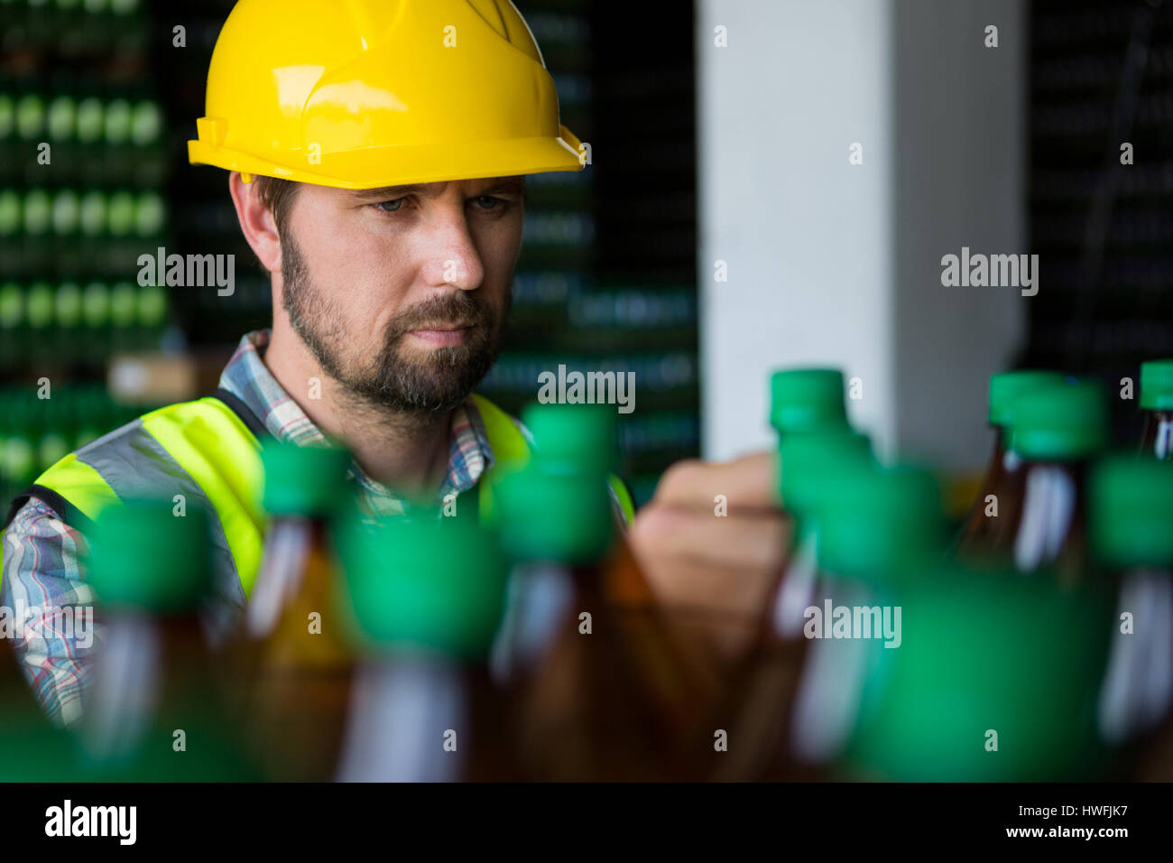 Serious man examining juice bottles in factory Stock Photo - Alamy