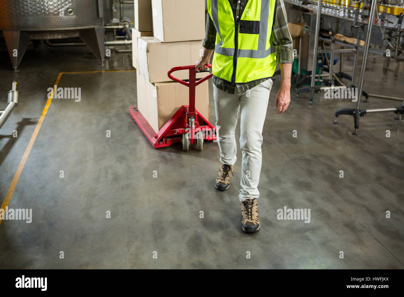 Low section of male worker pulling trolley in warehouse Stock Photo - Alamy