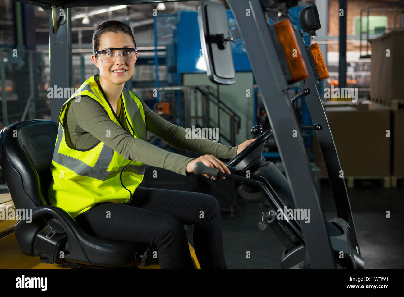 Portrait of beautiful female worker driving forklift in warehouse Stock ...