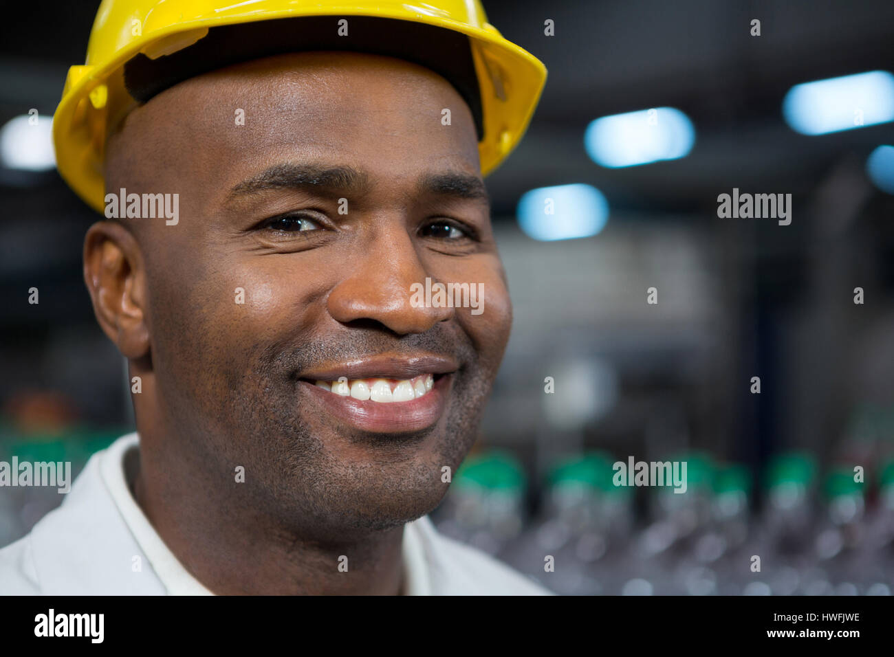 Close up portrait of smiling male worker wearing hard hat in warehouse ...