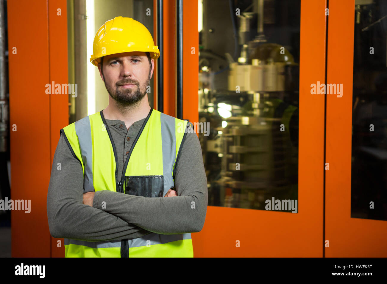 Portrait of confident male worker standing against door at factory ...