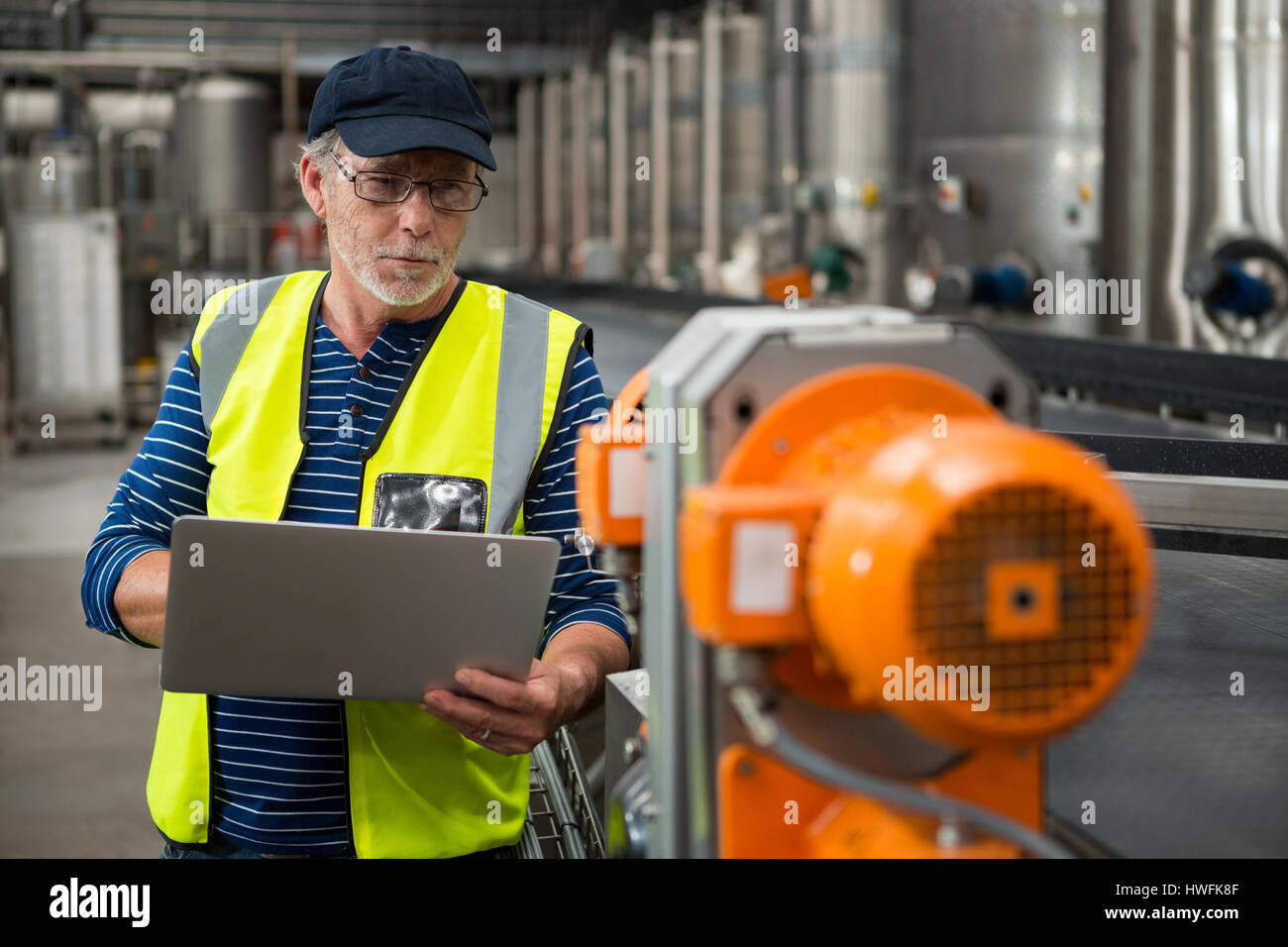 Manual worker analyzing machinery in factory Stock Photo - Alamy
