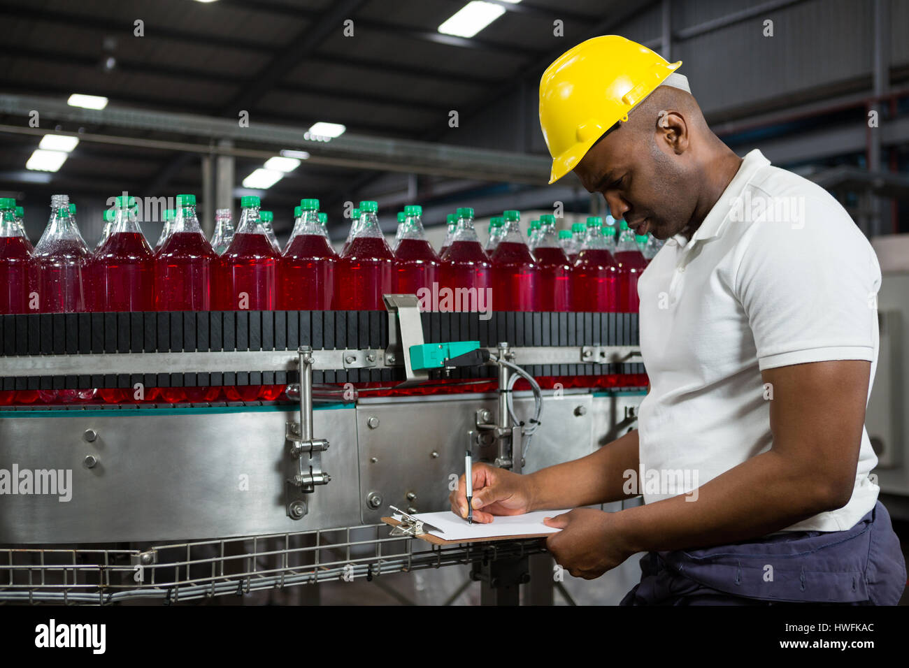 Young male worker noting about products in factory Stock Photo - Alamy