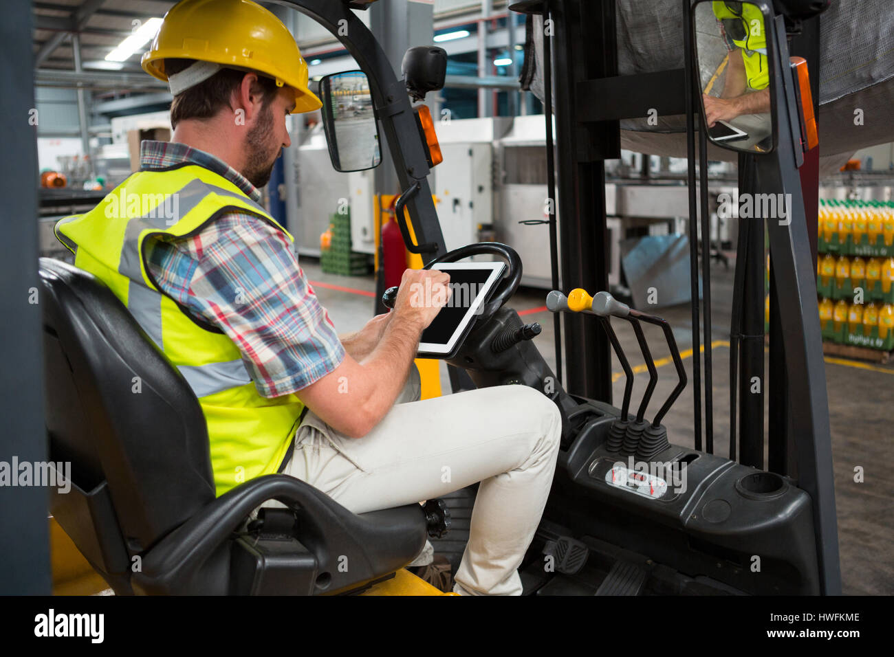 Confident male worker using digital tablet while sitting on forklift in ...
