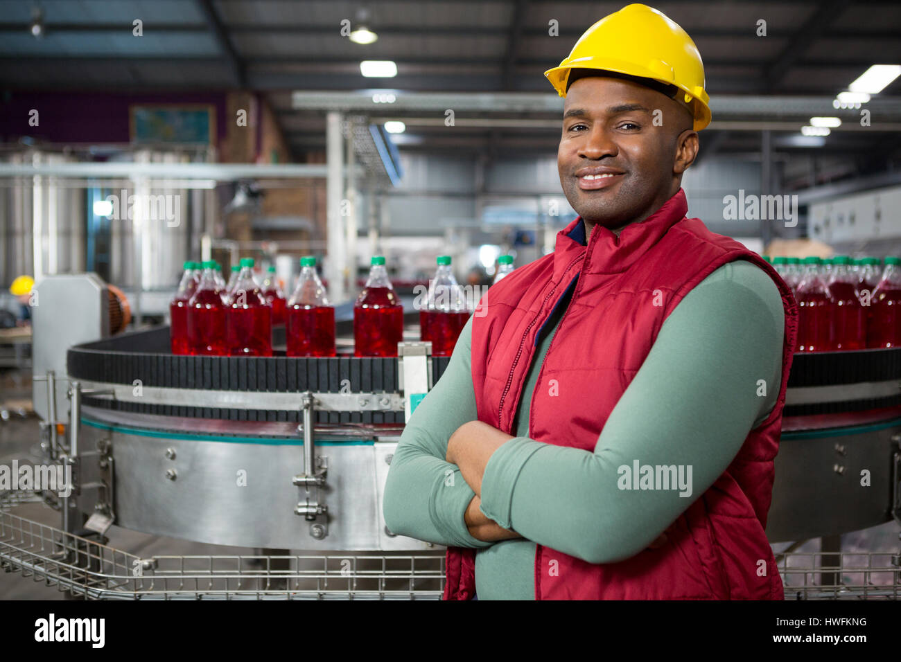 Portrait of confident male worker wearing red jacket at juice factory ...