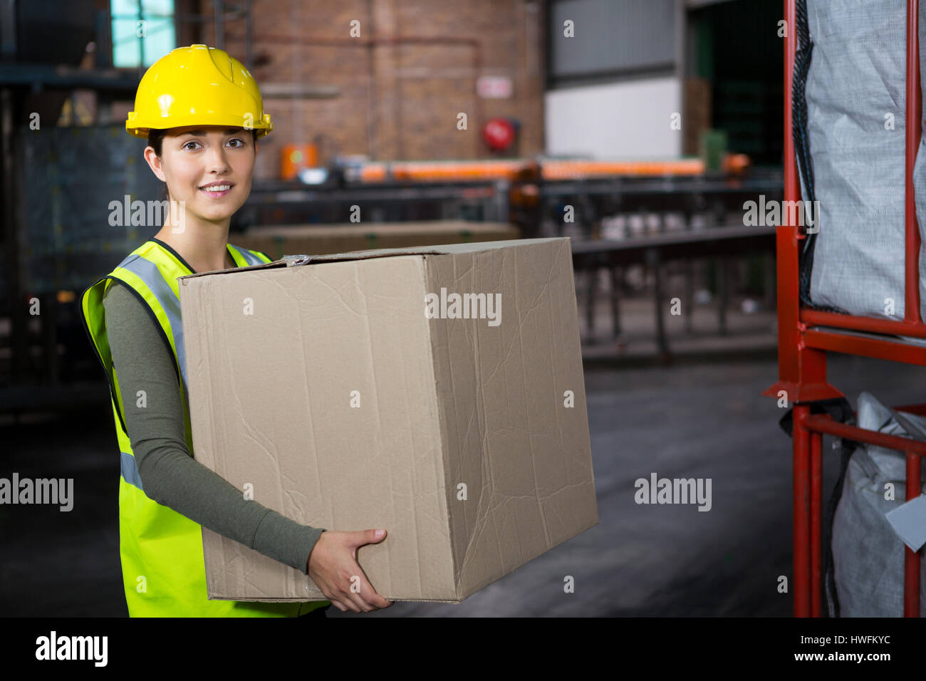 Portrait of beautiful female worker carrying box in warehouse Stock ...