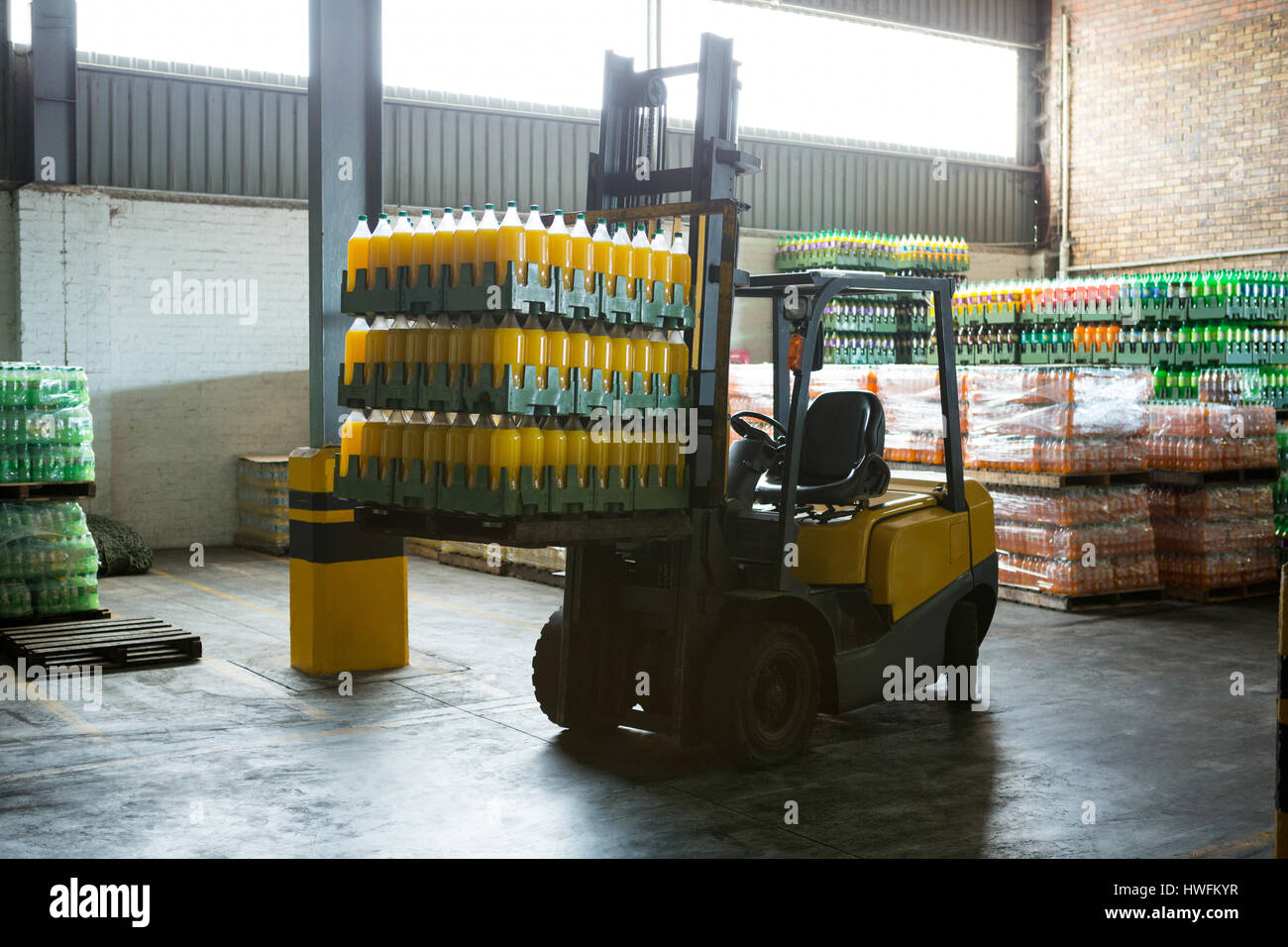 Stack of packed juice bottles and forklift in distribution warehouse ...