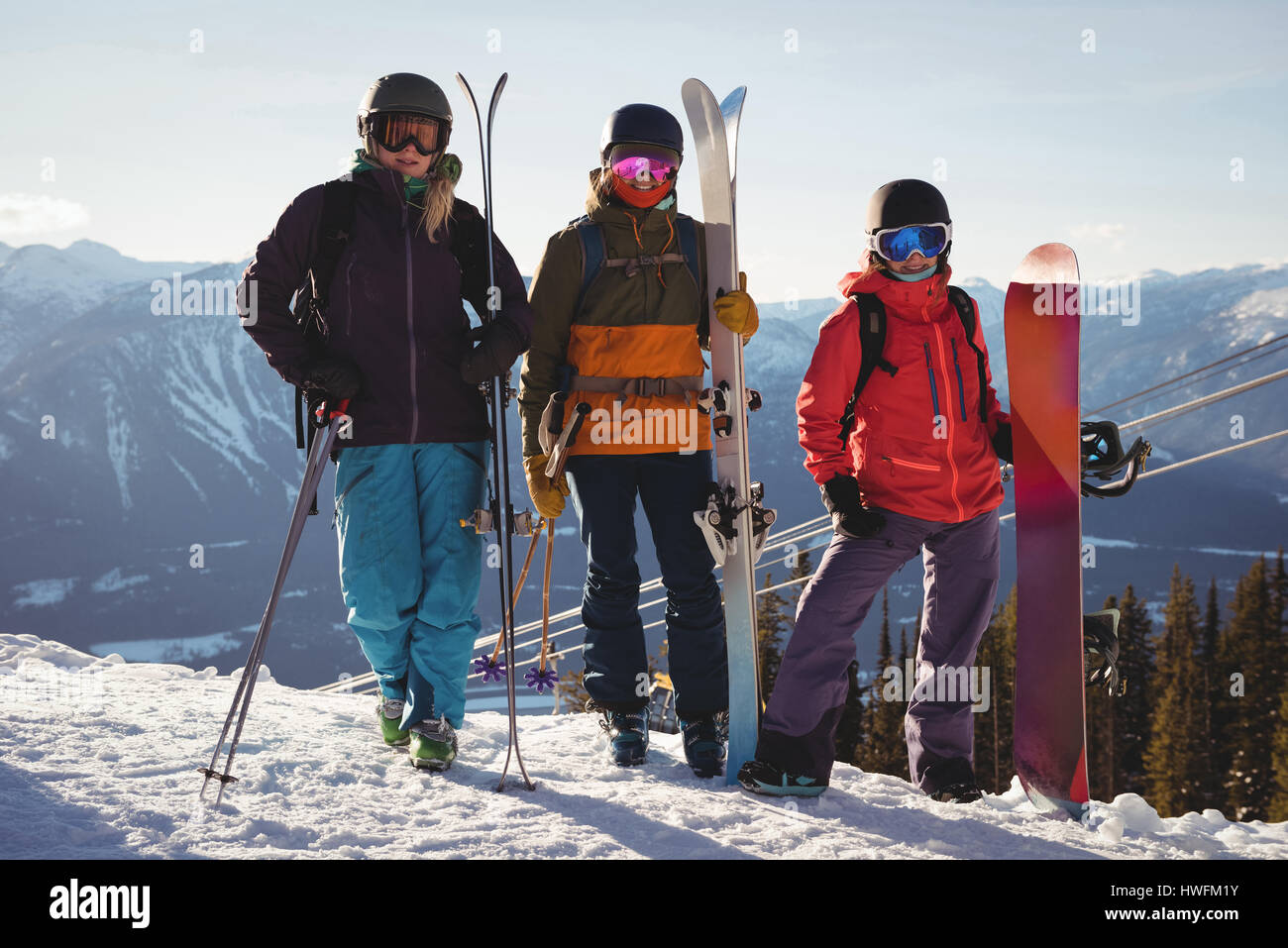 Three skiers with skies standing on snowy landscape in ski resort Stock ...