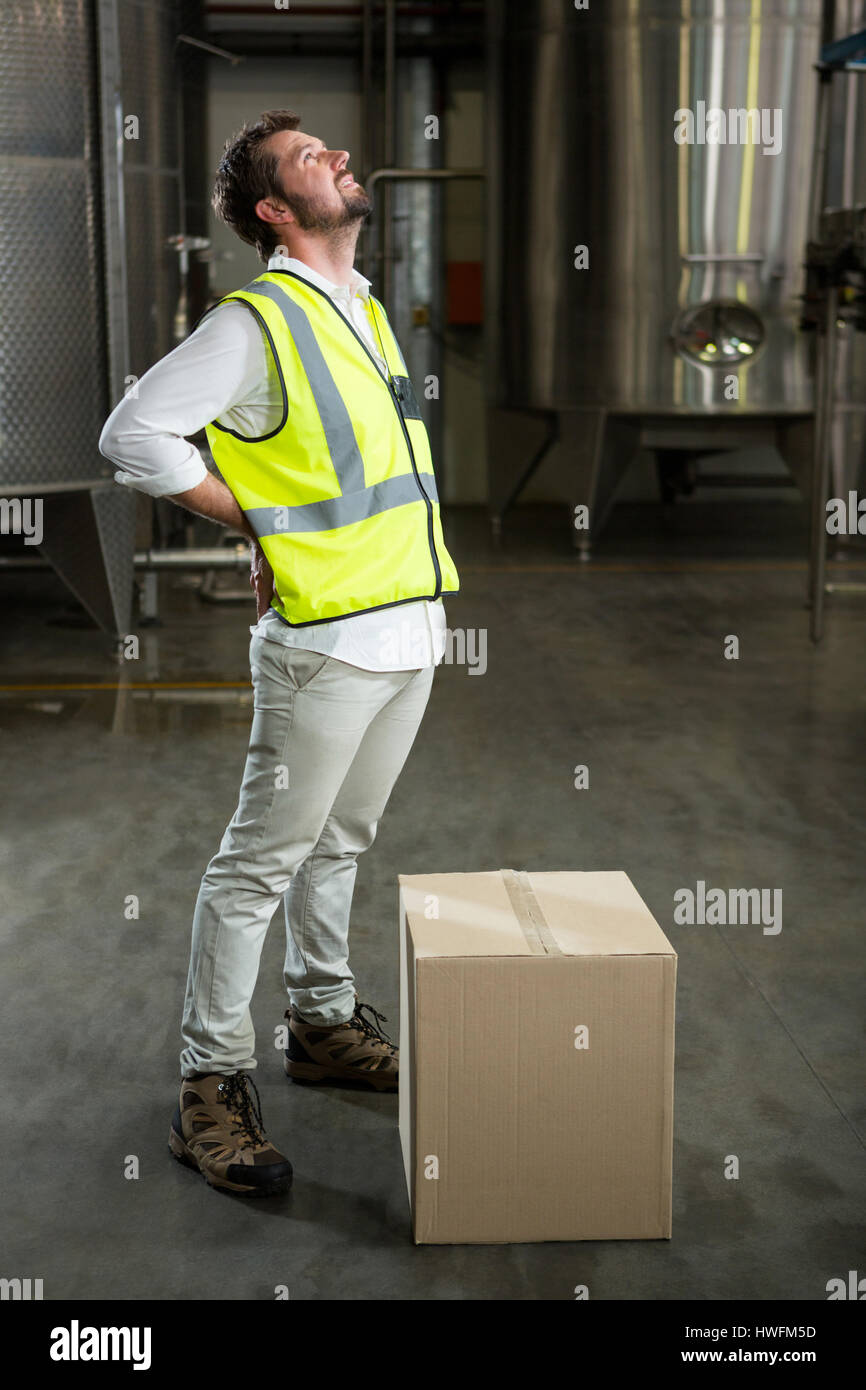 Full length of tired male worker standing in warehouse Stock Photo - Alamy