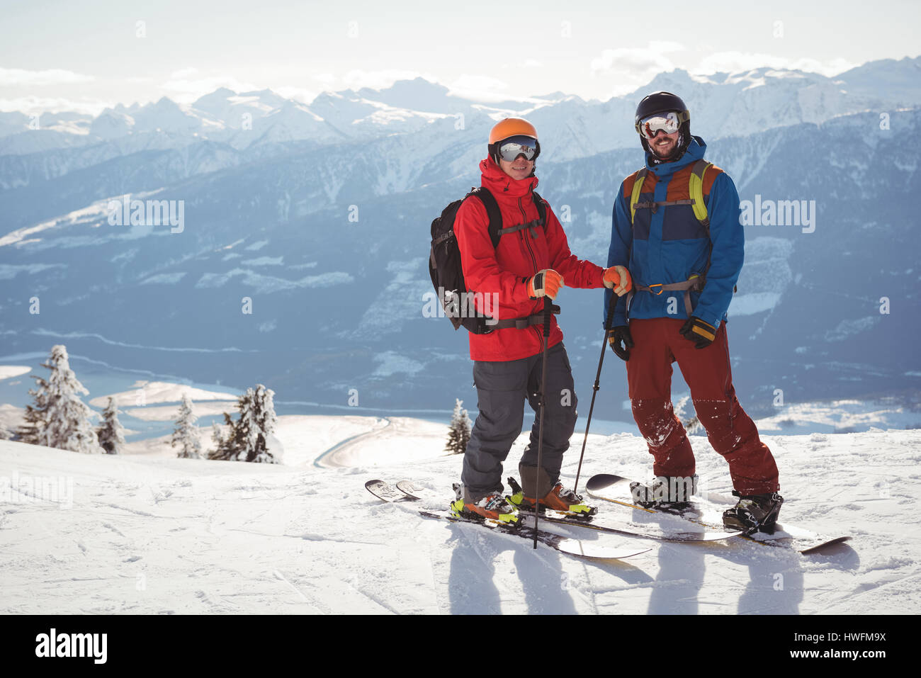 Two skiers standing together on snow covered mountain during winter ...