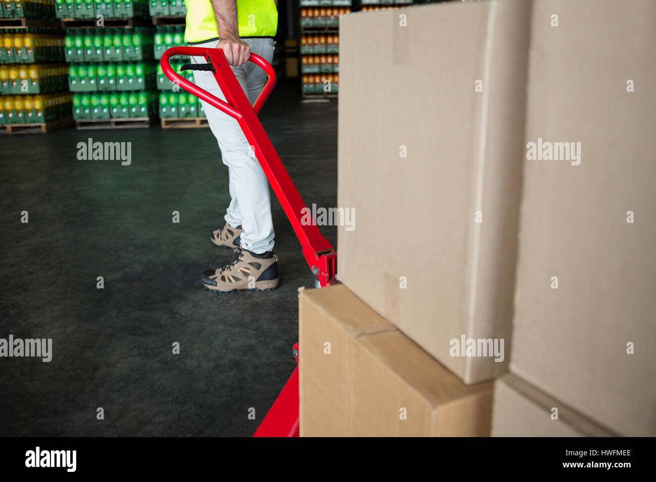 Low section of worker pulling trolley in warehouse Stock Photo - Alamy