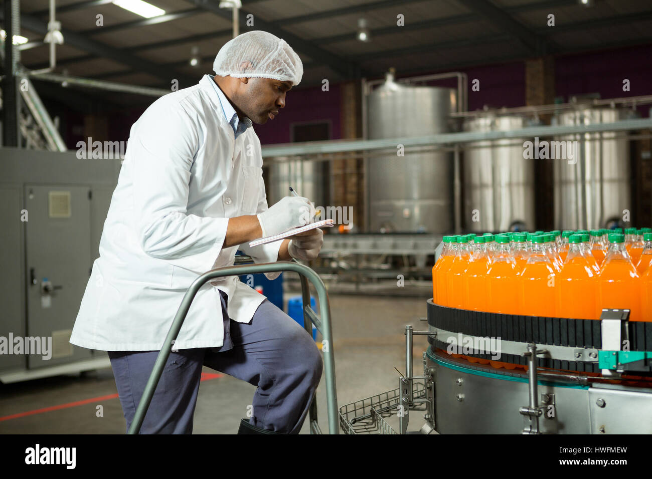 Male worker checking bottles in juice factory Stock Photo - Alamy