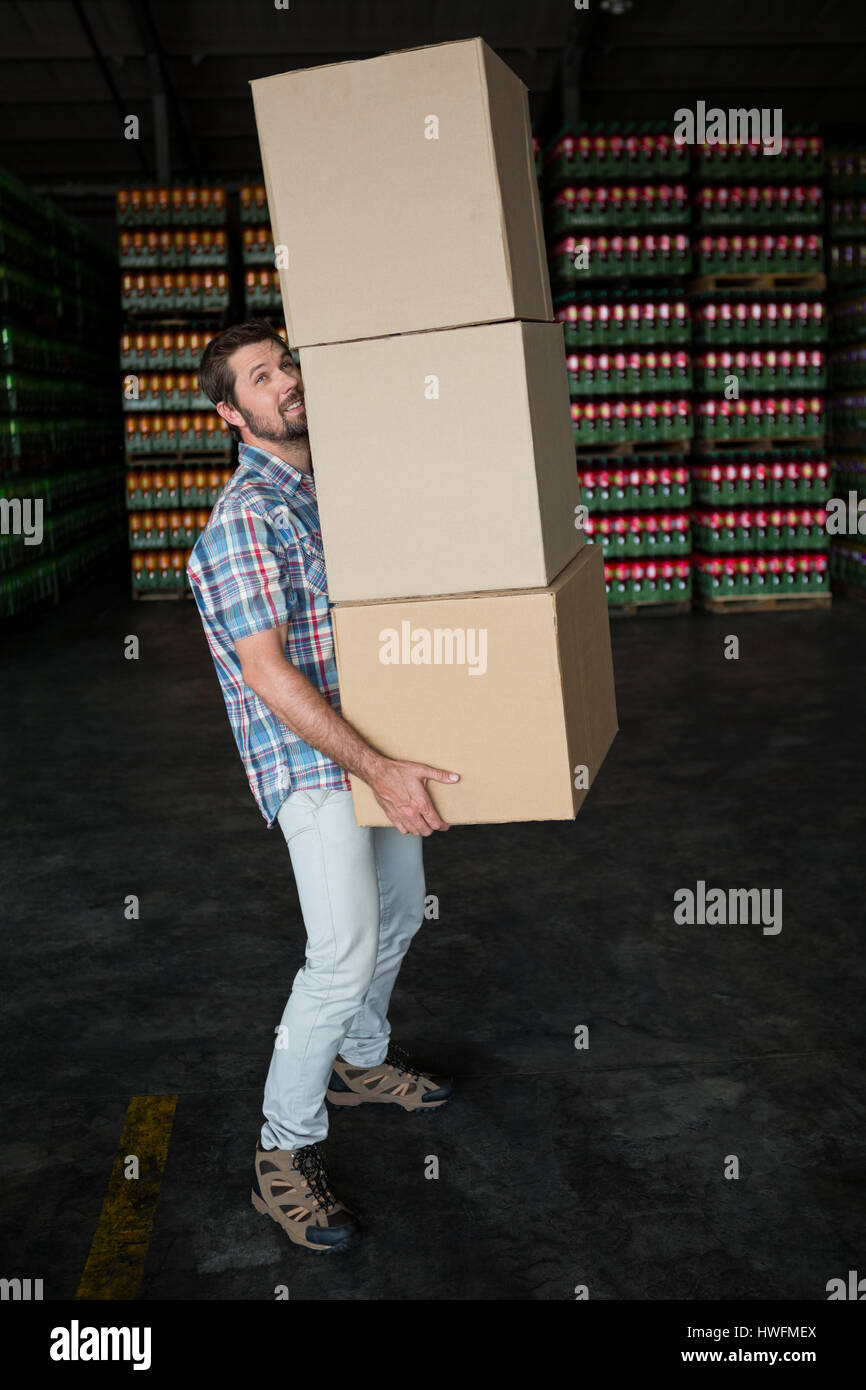 Side view of man carrying cardboard boxes in warehouse Stock Photo - Alamy