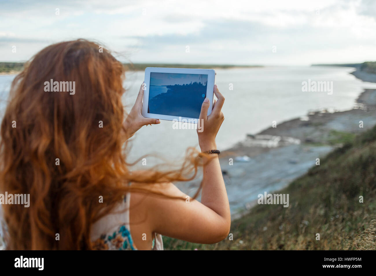 Back view of a young woman wanderer is making photo with portable ...