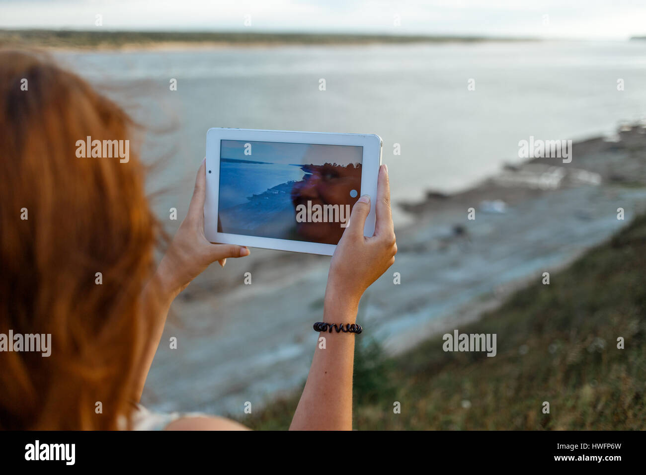 Back view of a young woman wanderer is making photo with portable ...