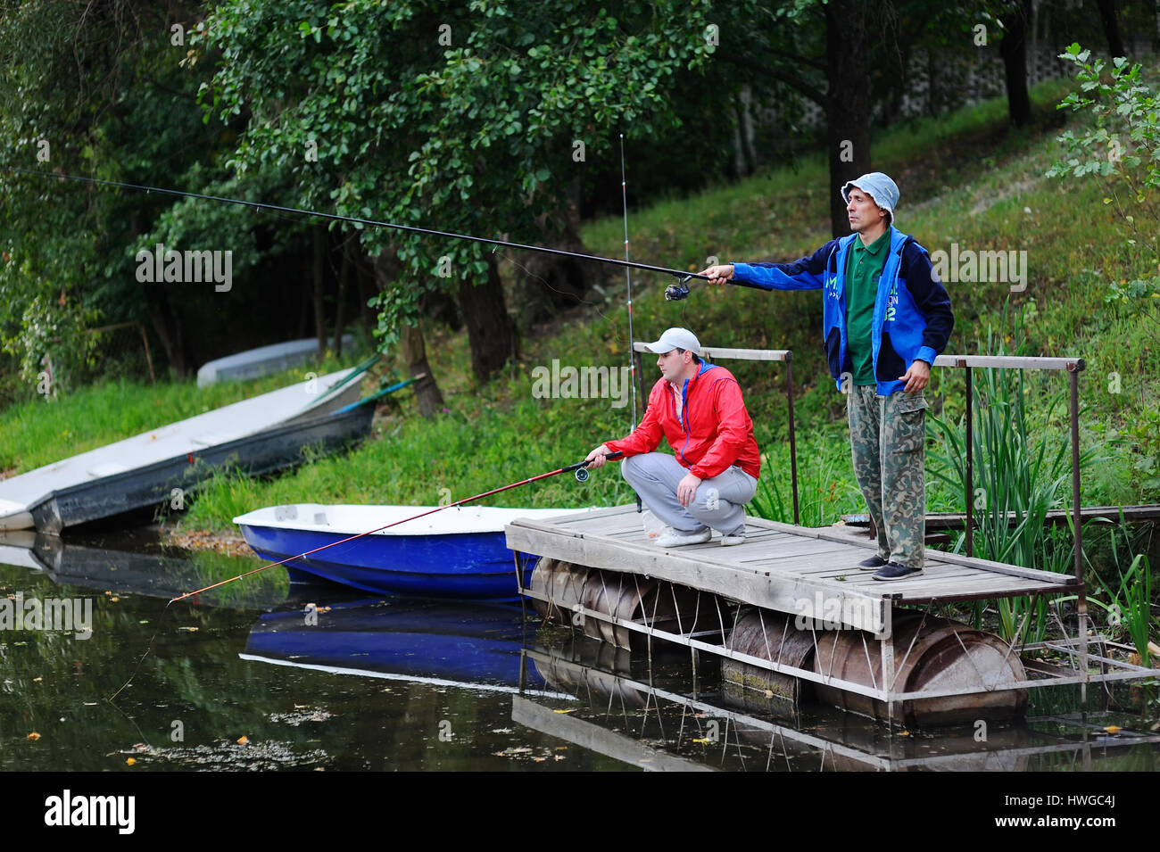 Two fishermen catch fish standing on the bridge Stock Photo - Alamy