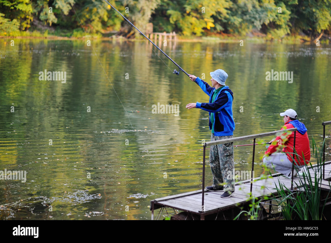 Two fishermen catch fish standing on the bridge Stock Photo - Alamy